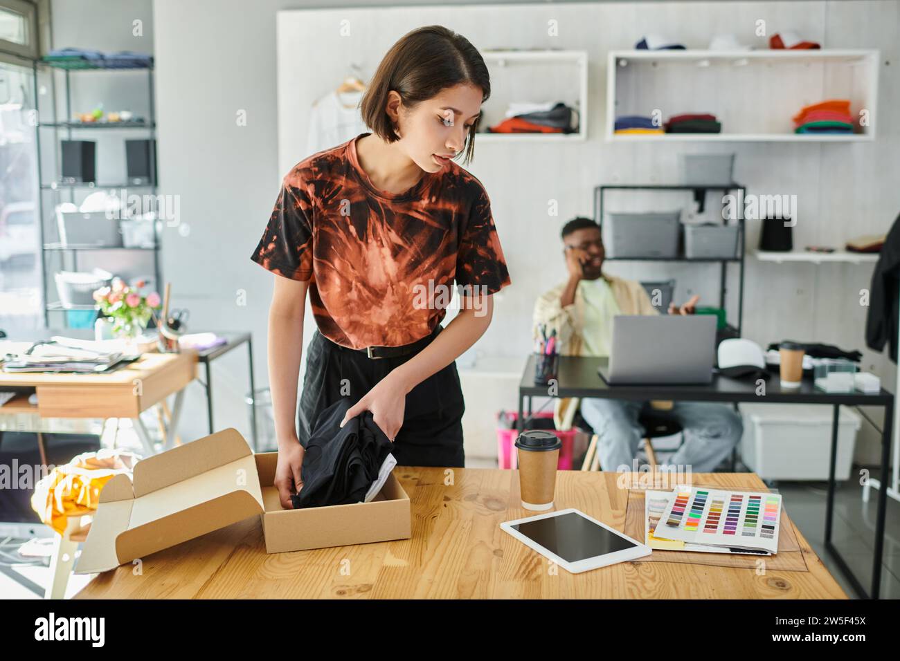 asian worker of print studio packing clothes near digital tablet and ...
