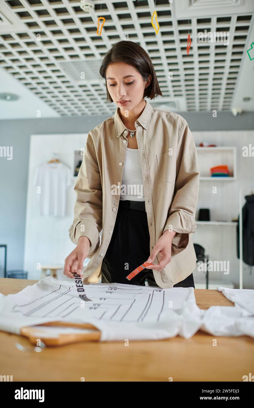 young female asian designer holding text template near clothing with ...