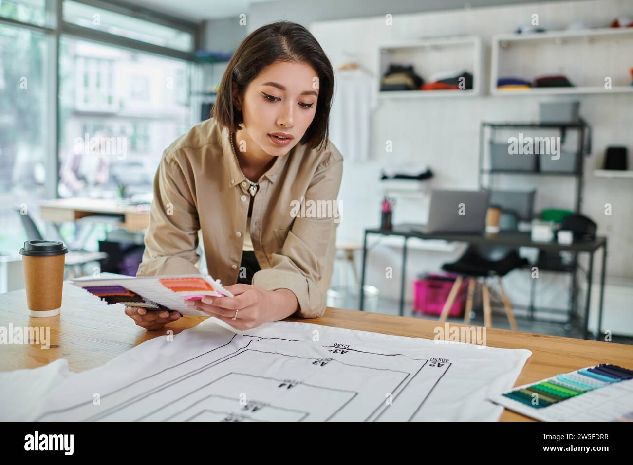 young asian designer with color palette near clothes with format sizes ...