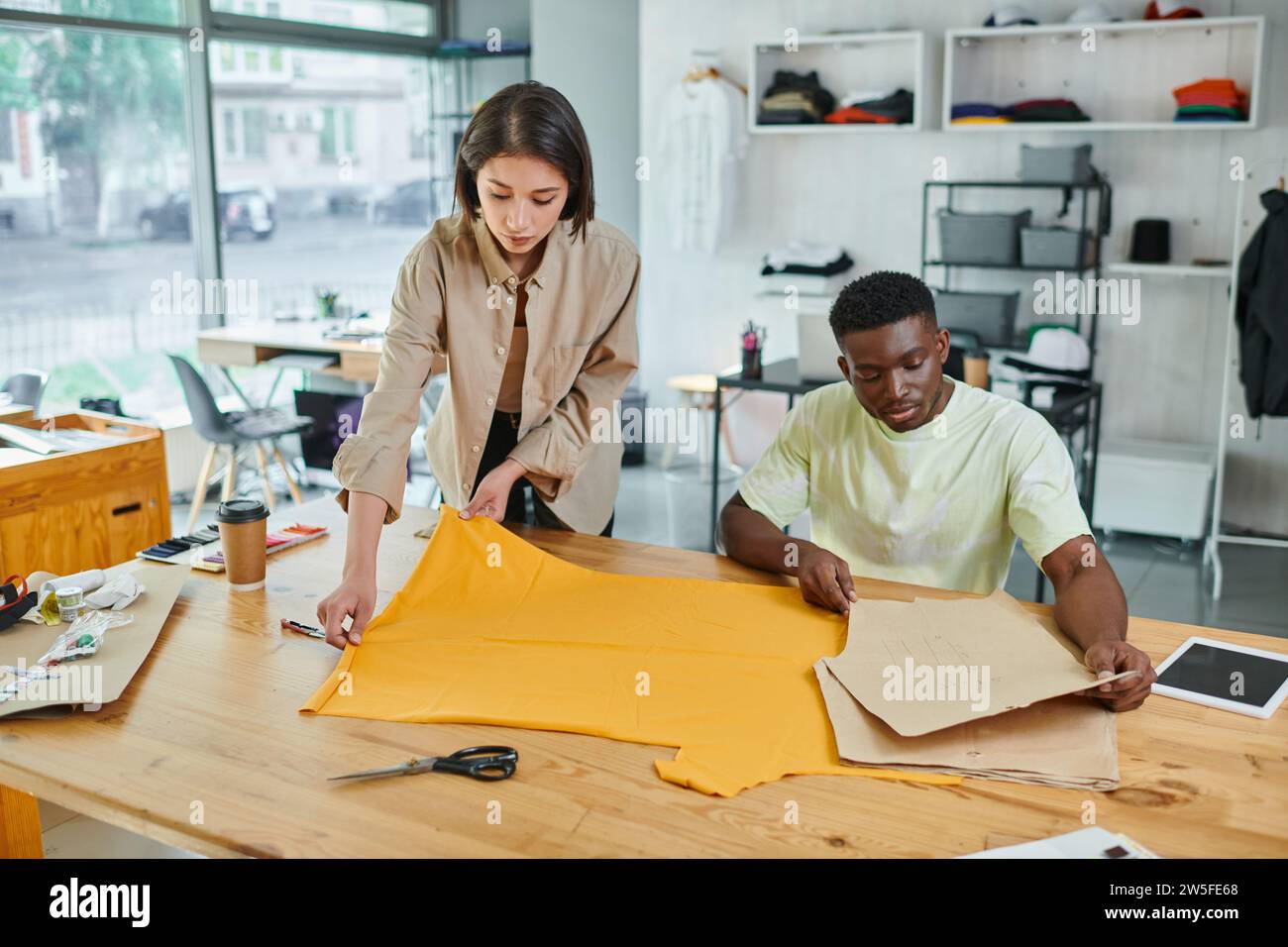 creative multiethnic fashion designers working with sewing patterns in ...