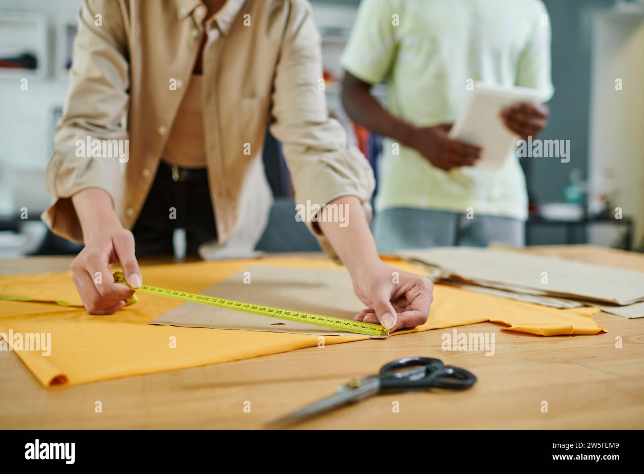 partial view of female fashion designer measuring sewing patterns in ...