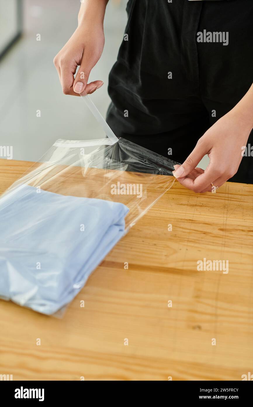 partial view of diligent female worker packing folded clothes in ...
