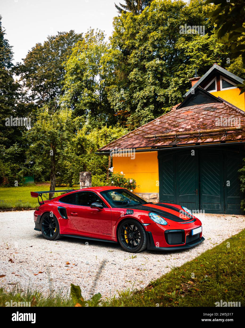 Hot red Porsche 911 GT2RS 991.2 parked in village in front of a small ...