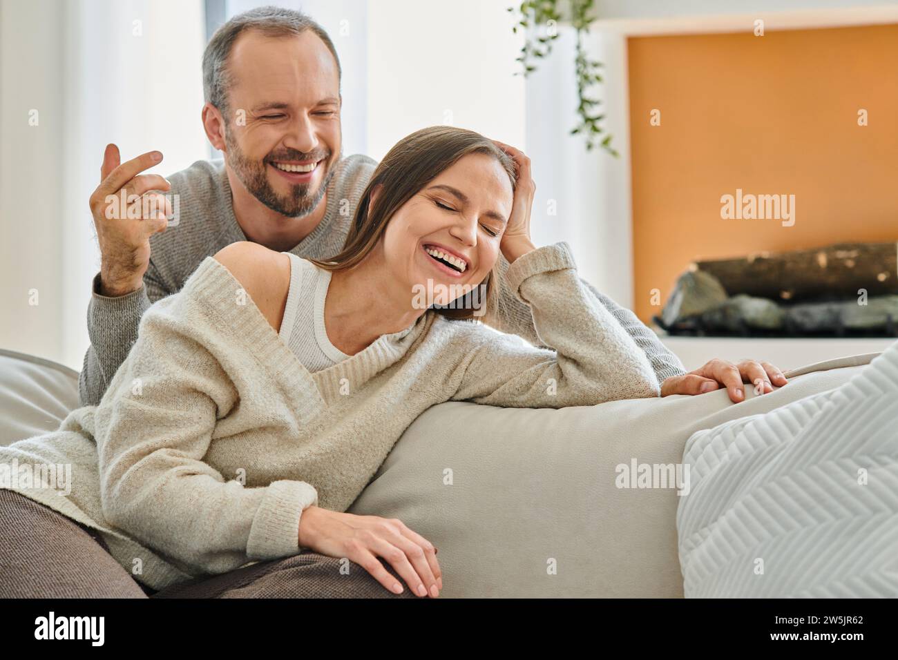 excited child-free couple laughing on couch in modern cozy living room ...