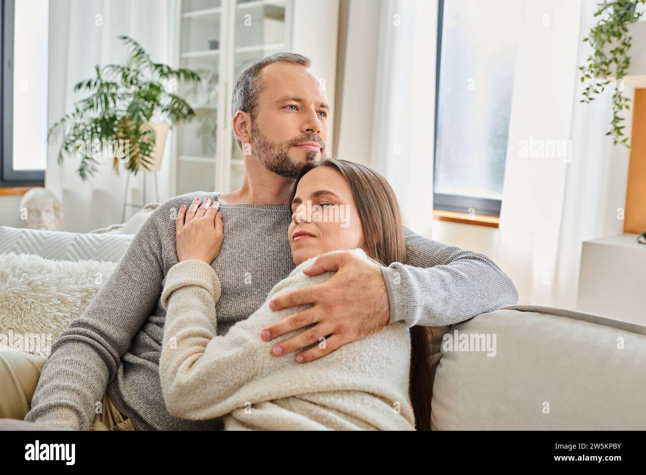 pleased child-free couple embracing on cozy couch in modern living room ...