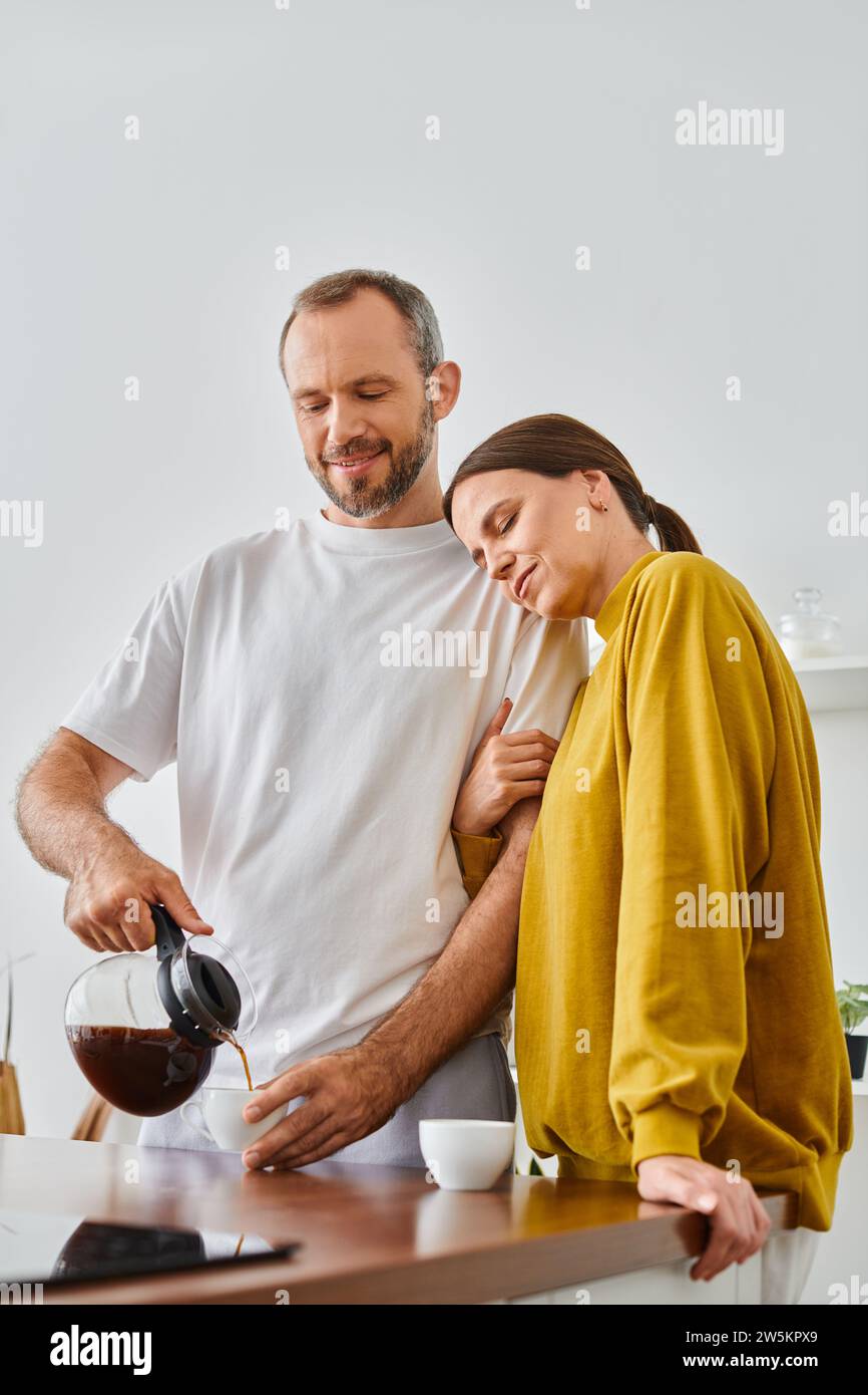 caring man pouring fresh aromatic coffee near happy wife in kitchen ...