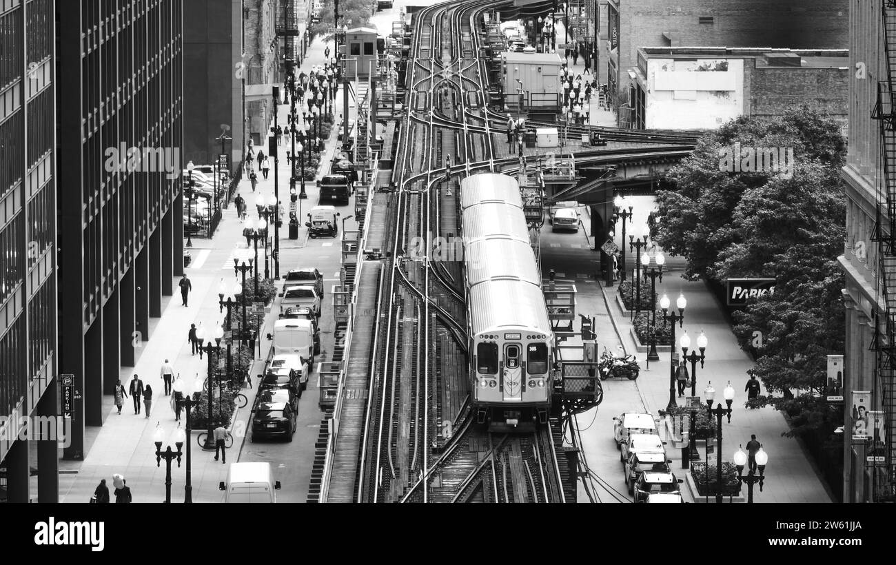 Train on track in black and white in big, inner city aerial of Chicago tourism transit and ...