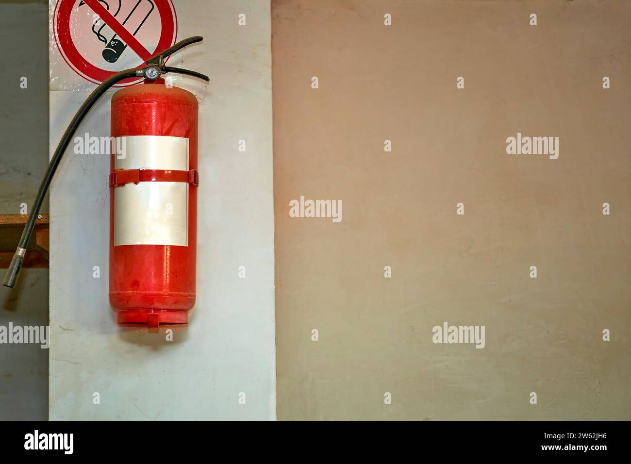 Fire extinguisher on the wall in the basement with a no smoking sign ...
