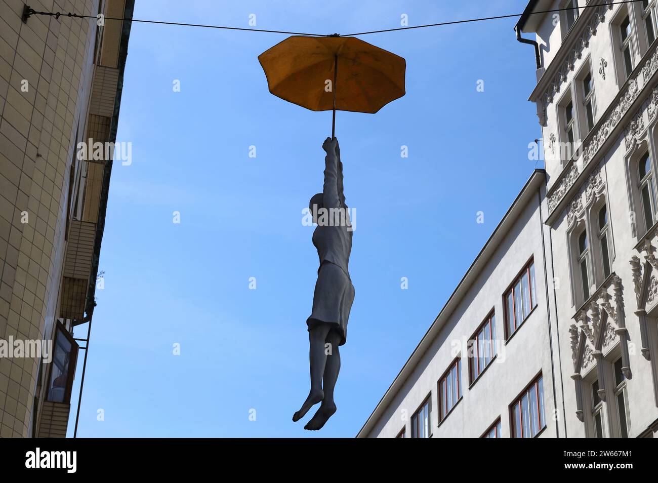 Sculpture of woman hanging from an umbrella suspended high above a ...