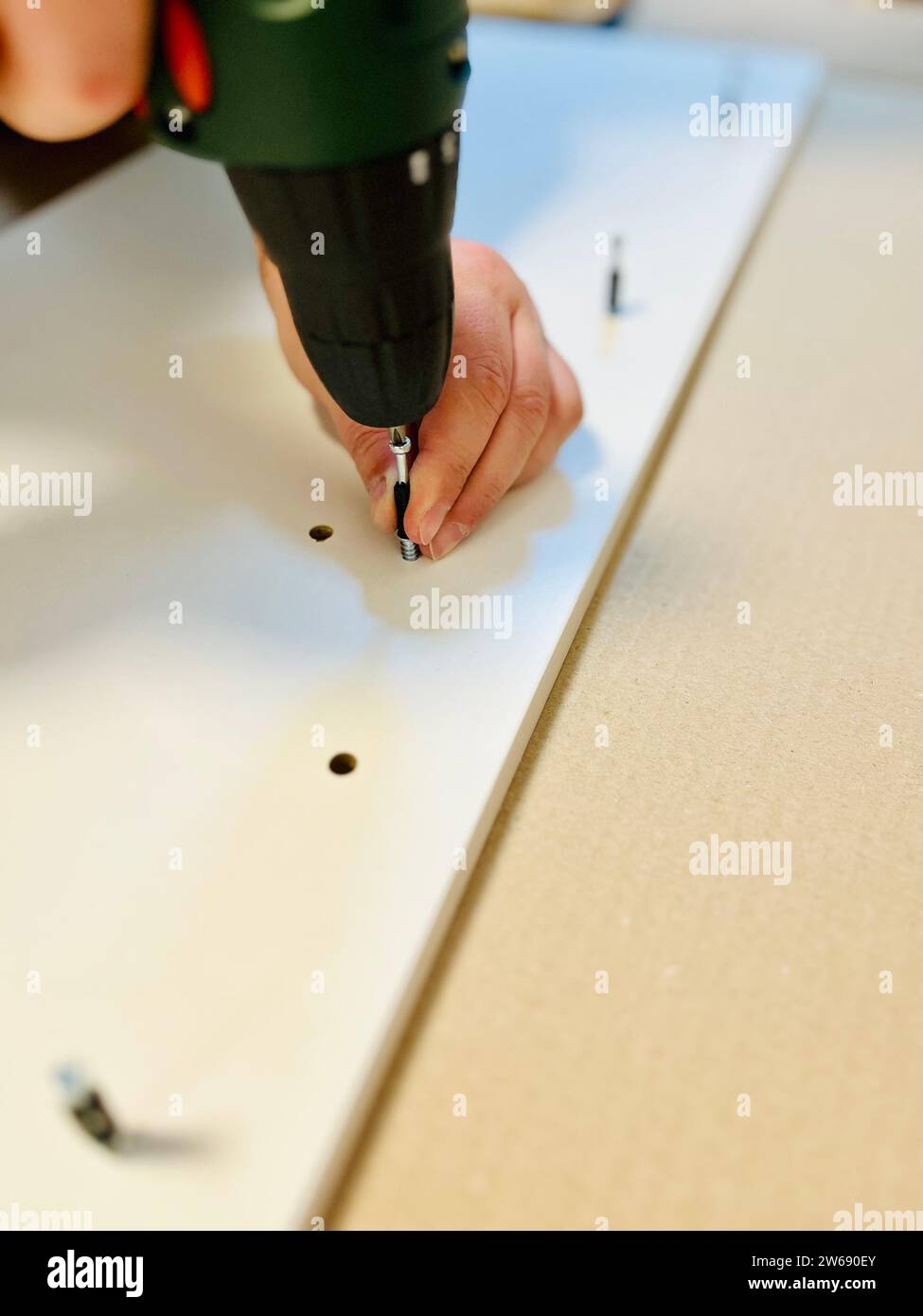 Close-up of a man's hands using an electric screwdriver to assemble a ...