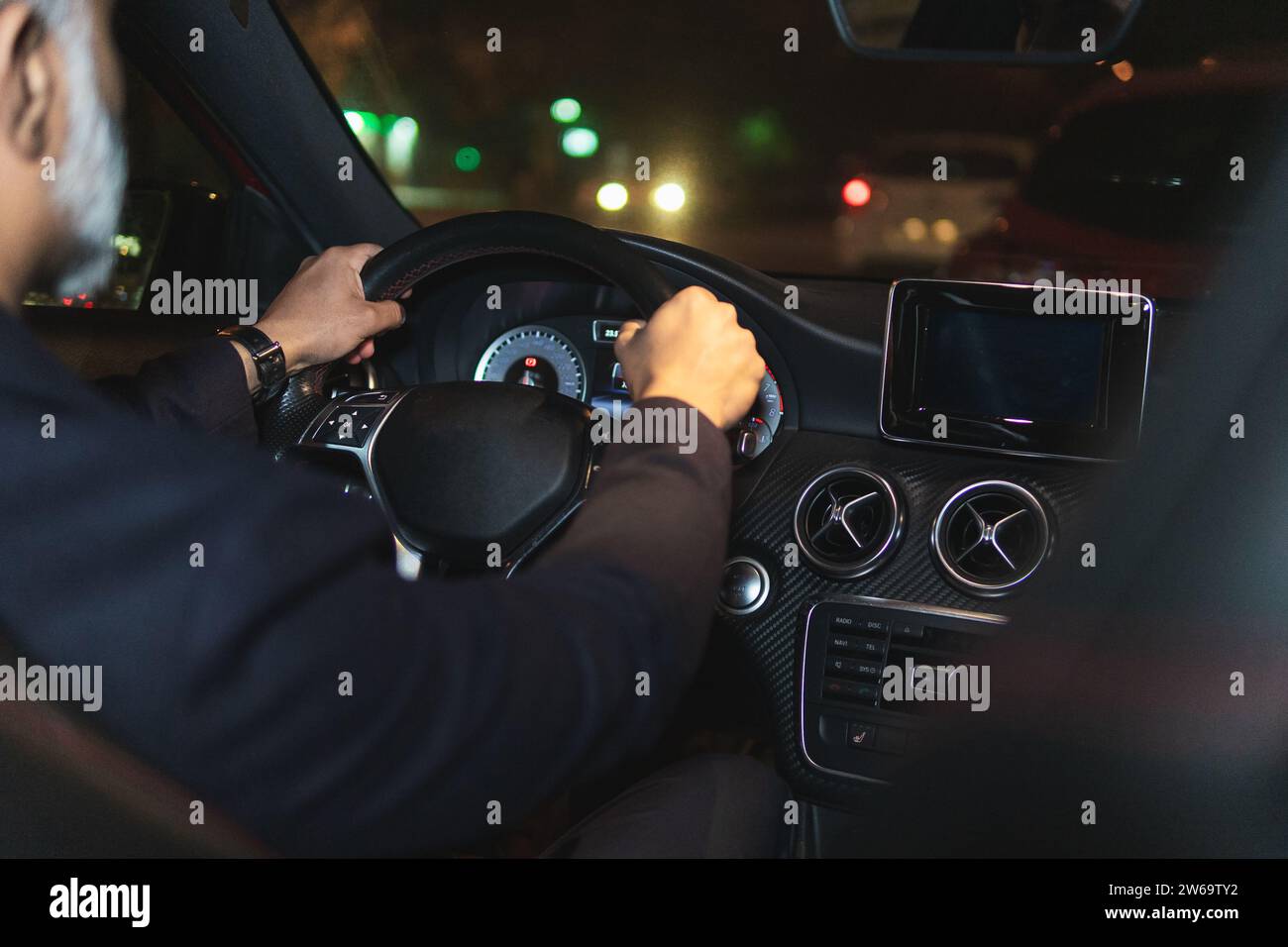 Back view of anonymous businessman in formal clothes driving car along ...