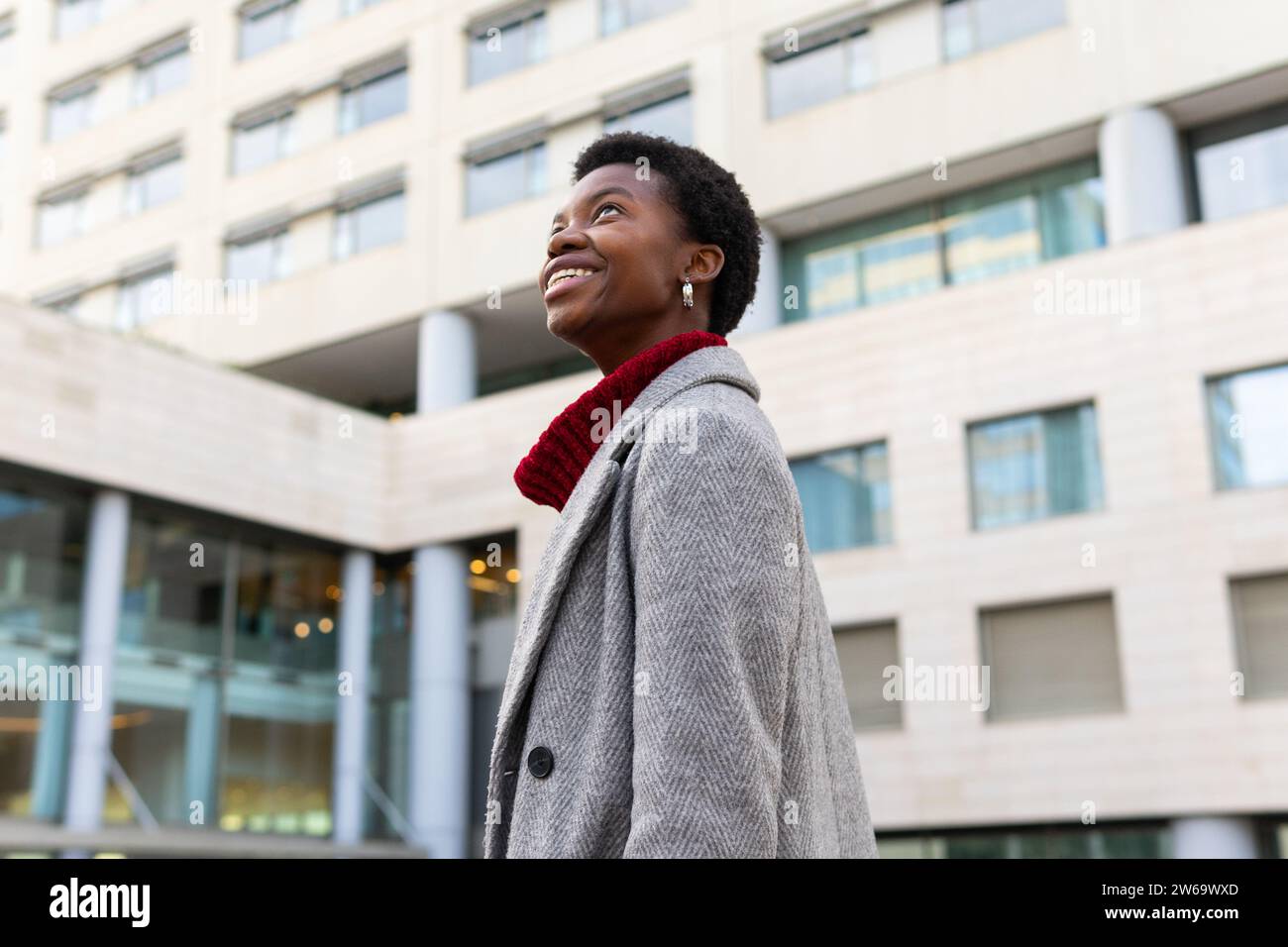 Low angle side view of smiling young African American female standing ...