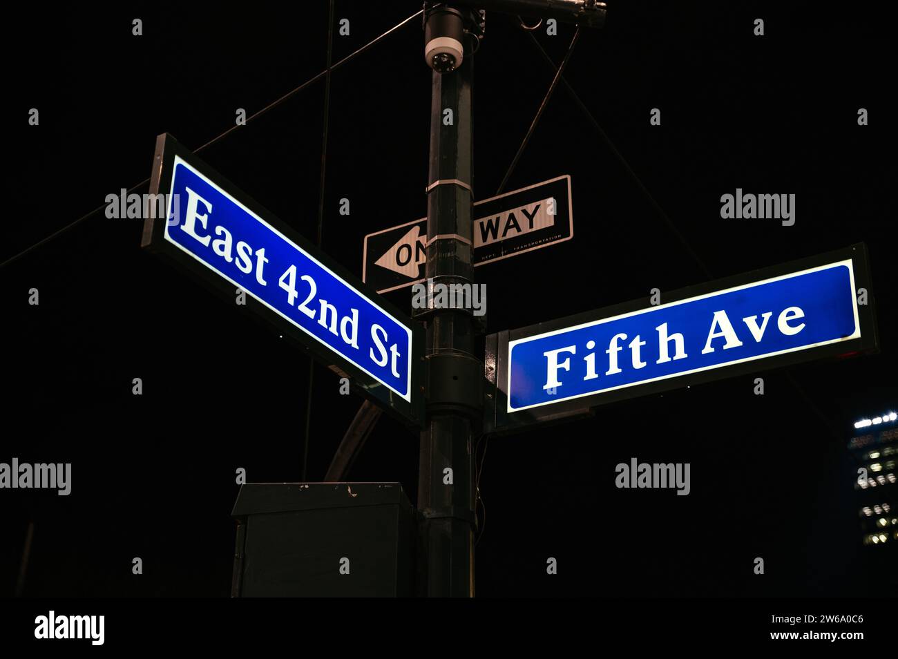 Low angle of road sign with names of streets and avenues against night ...