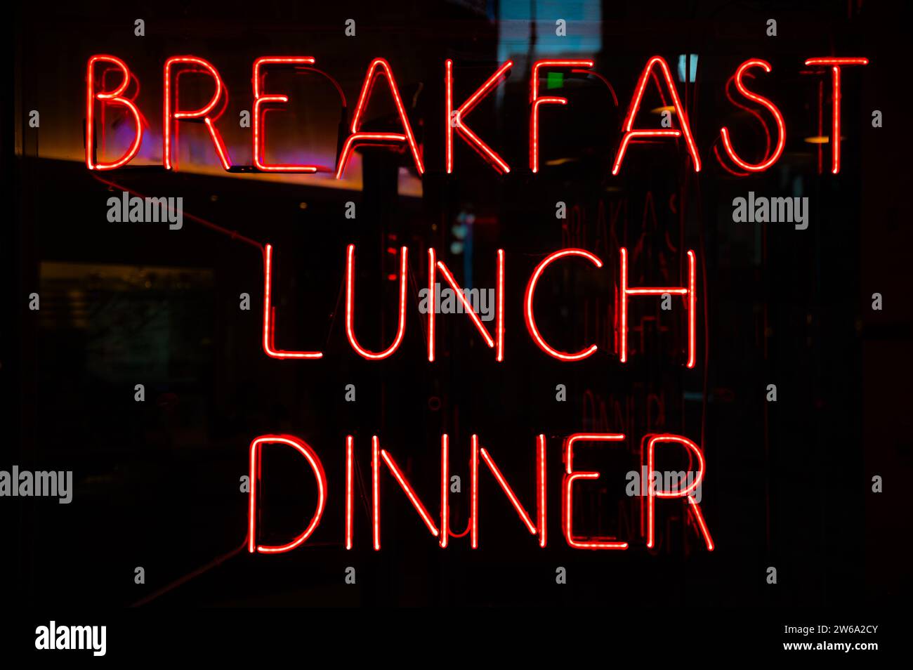 Vibrant red neon signs advertising breakfast, lunch, and dinner glow in ...