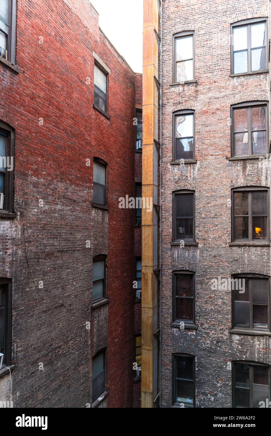 A narrow alleyway between old brick buildings with multiple windows and ...