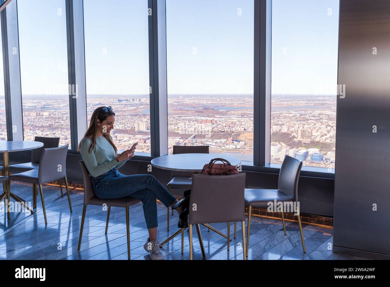 A woman comfortably seated at a high-rise cafe table, engrossed in her ...