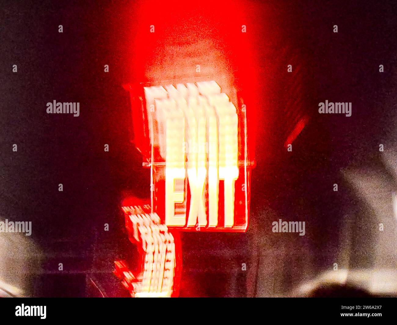 Blurry illuminated glowing bright red EXIT neon sign on building facade ...