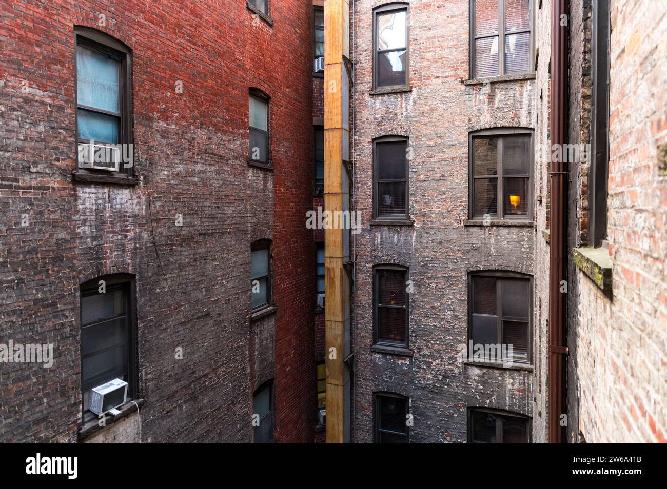 A narrow alleyway between old brick buildings with multiple windows and ...