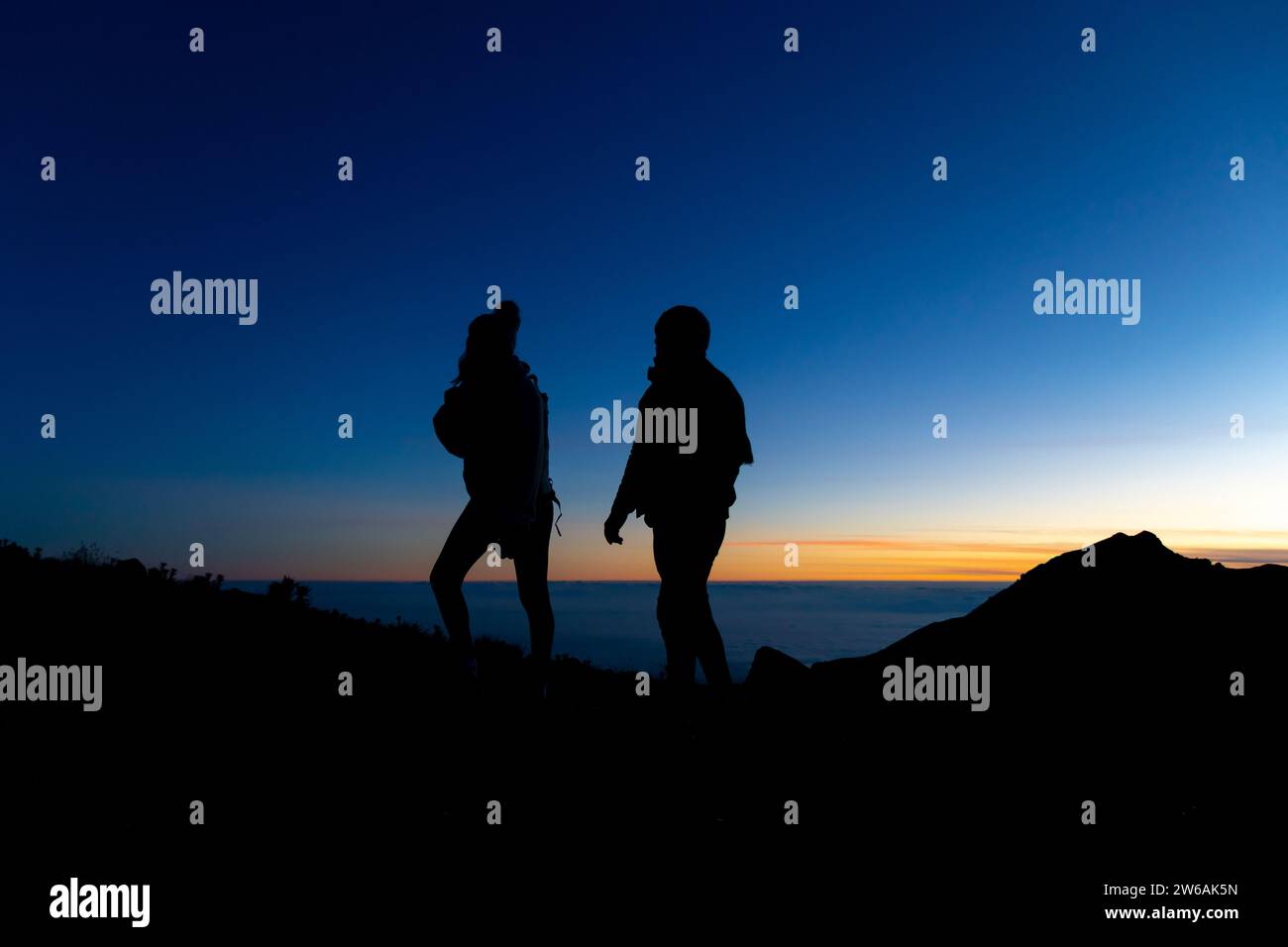 Side view of silhouettes of anonymous traveler couple in warm clothes ...