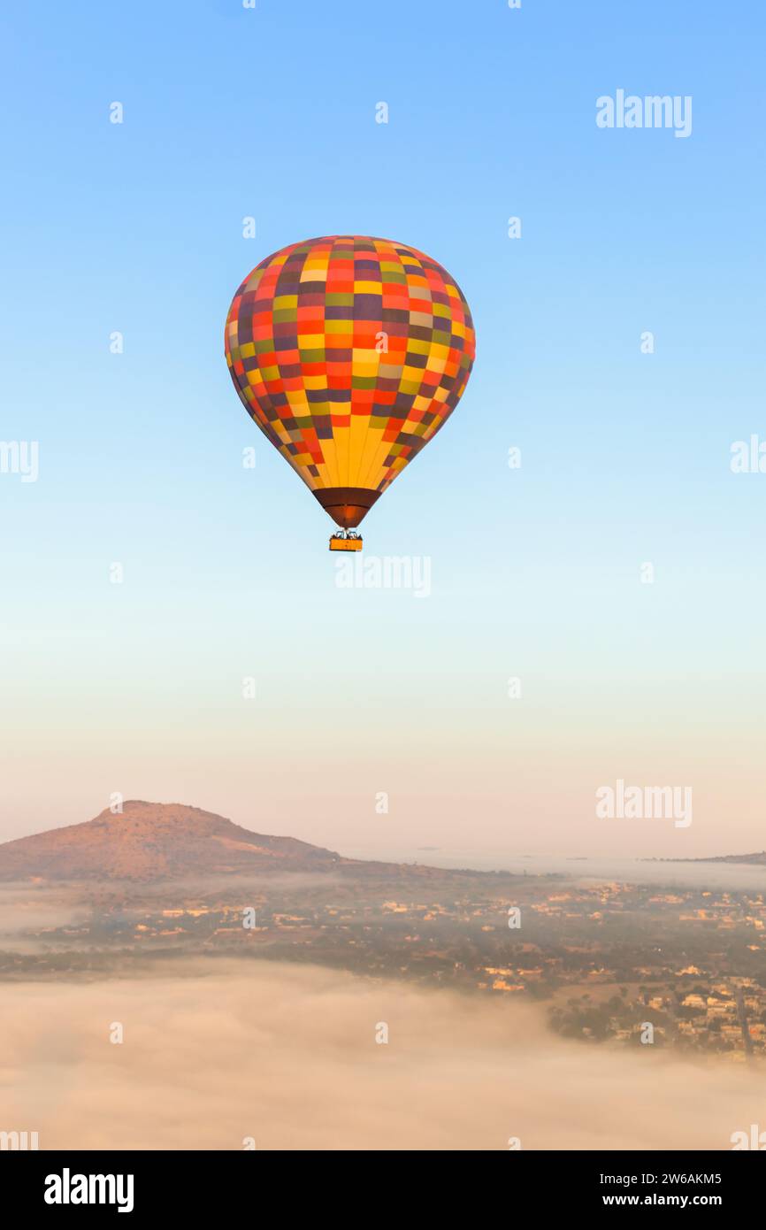 Hot air balloon floats in sky mist-covered landscape Stock Photo - Alamy