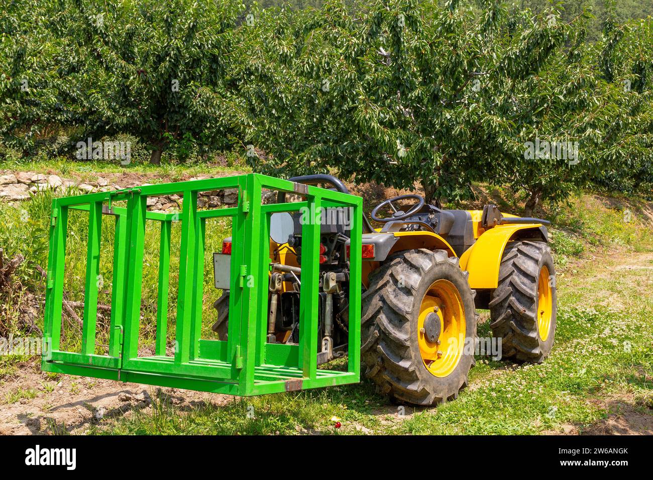 Yellow tractor with specialized green metallic hydraulic harvester on ...