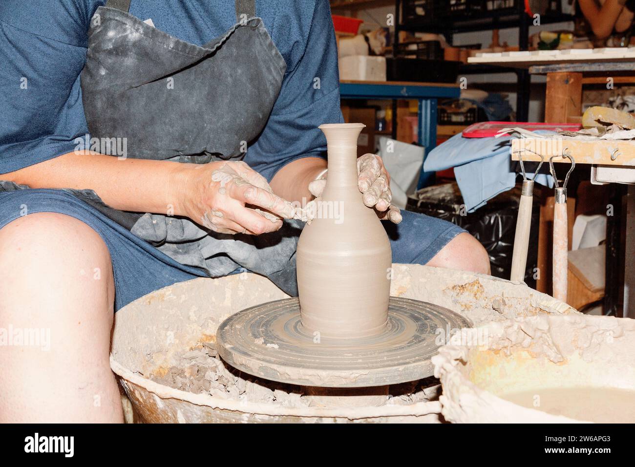 Skillful crop anonymous artisan shaping clay vase with instrument on ...