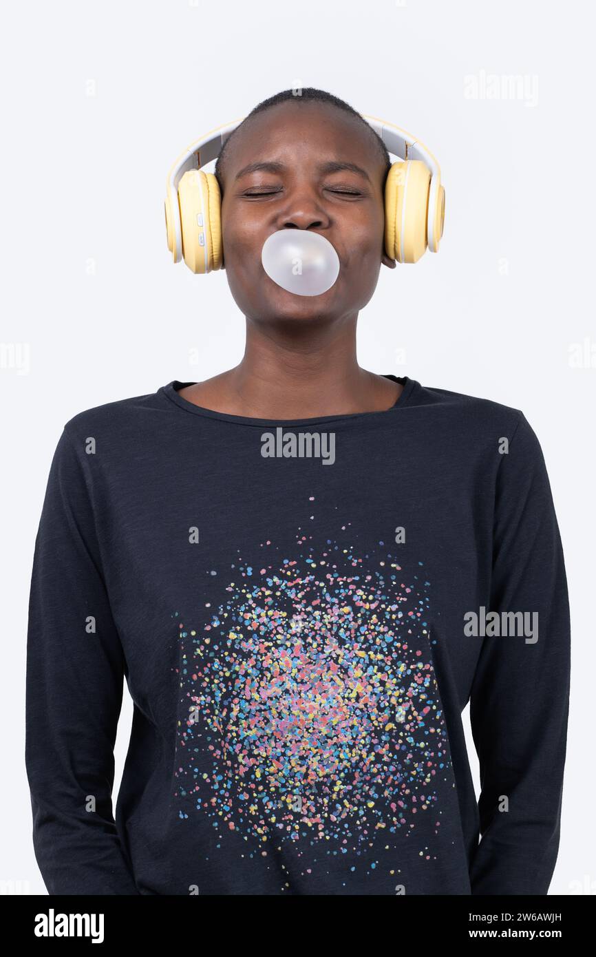 Contented black young woman with eyes closed listening music through ...