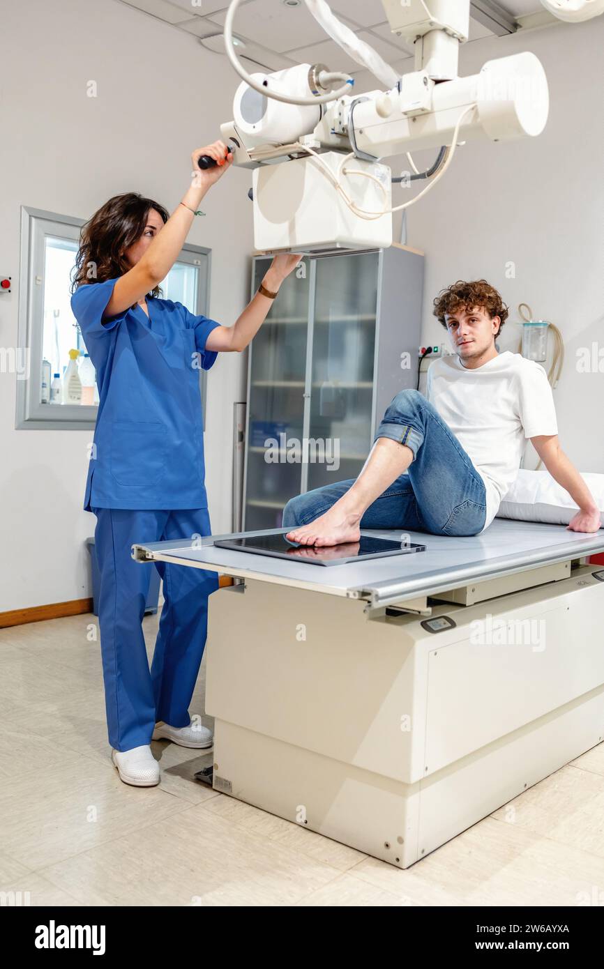 Full body of female nurse in blue uniform adjusts X Ray machine for ...