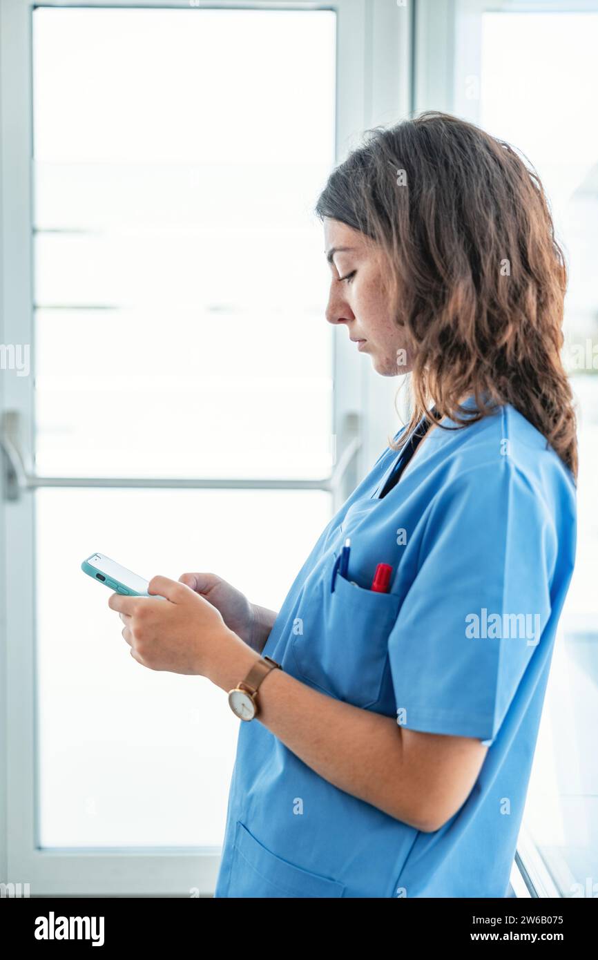 Side view of young female doctor wearing blue uniform standing in ...