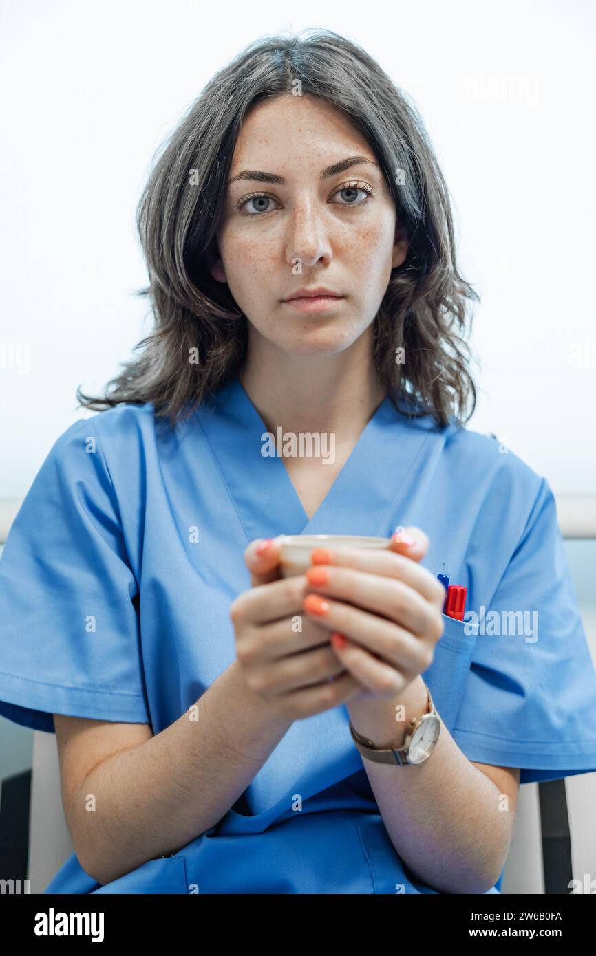 Young female doctor wearing blue uniform looking at camera while ...