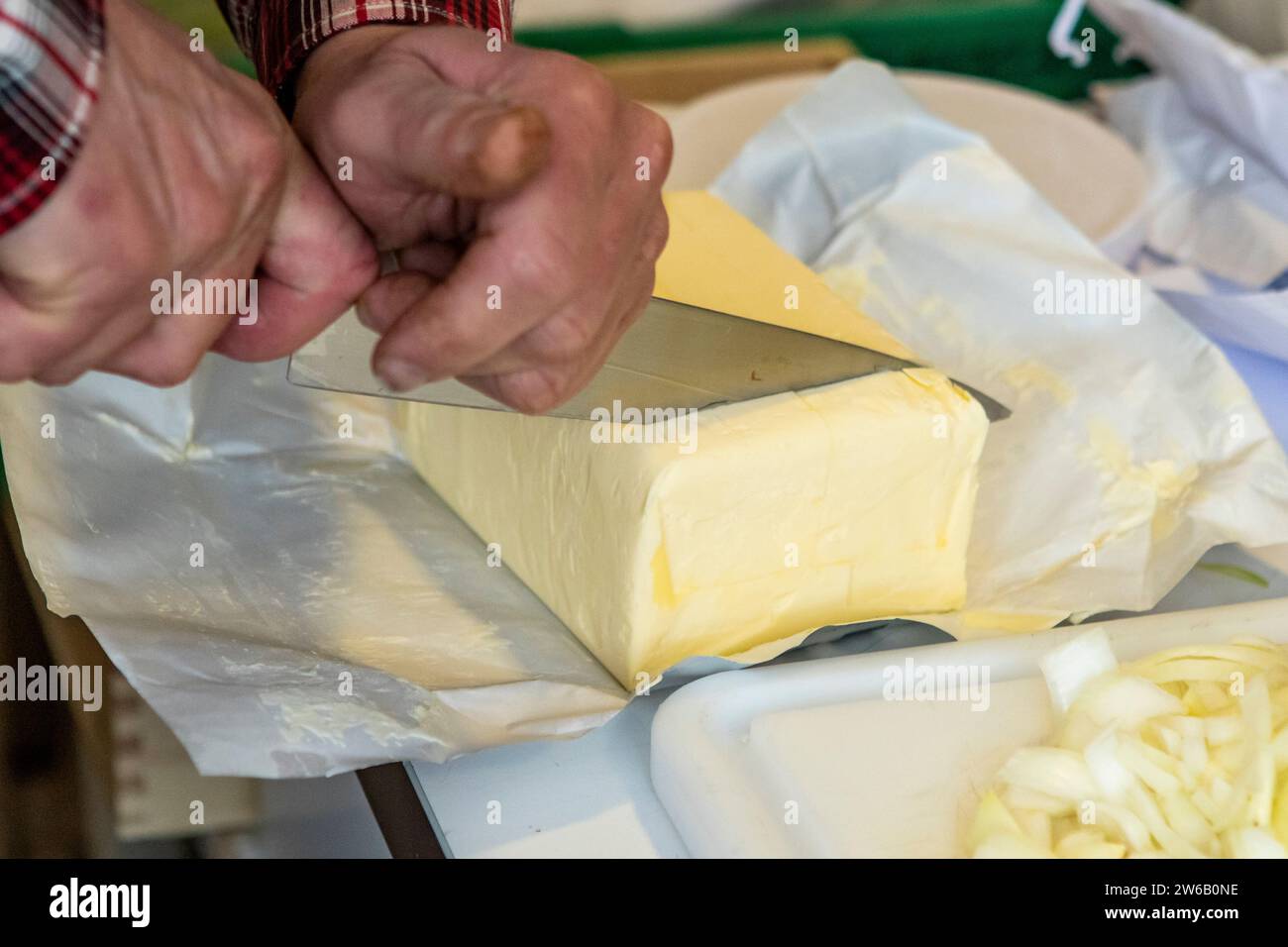 Close-up view of an anonymous chef's hands cutting a block of butter ...