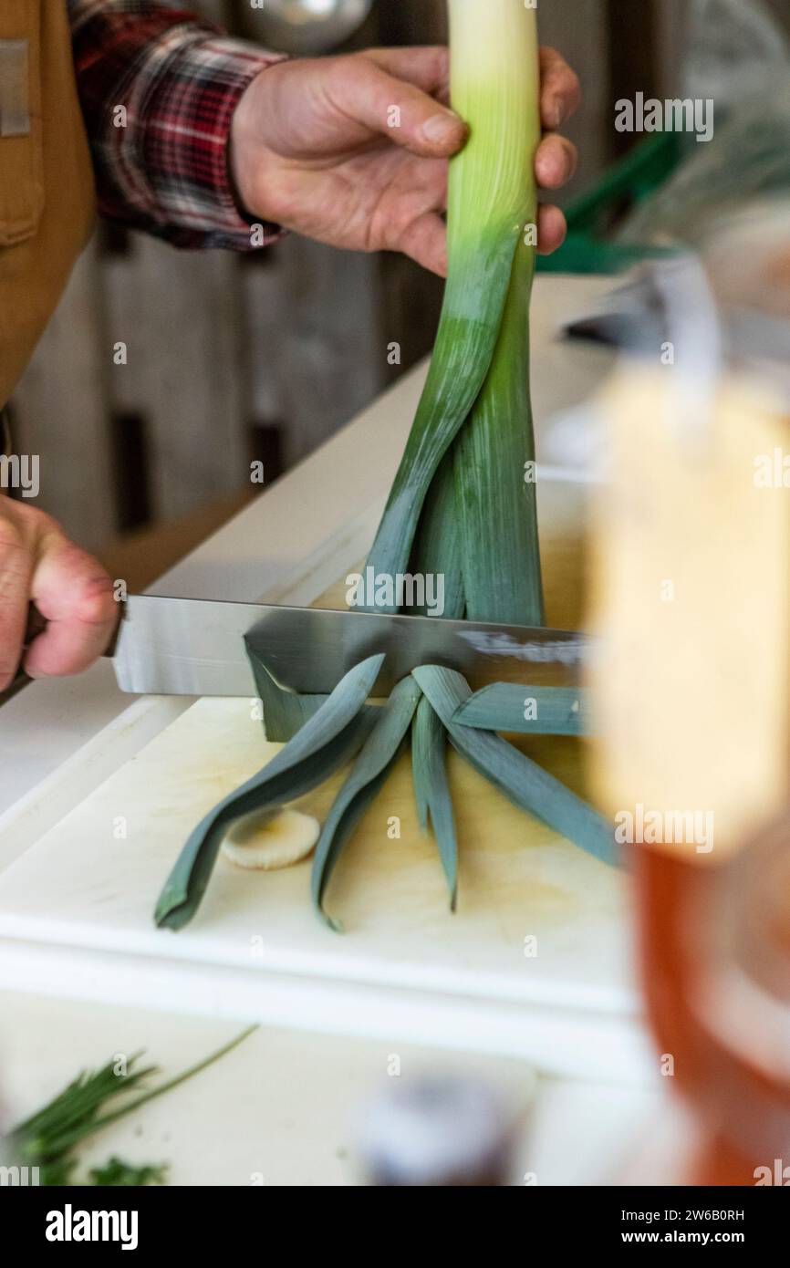High angle of anonymous chef's hands carefully preparing leeks on a ...