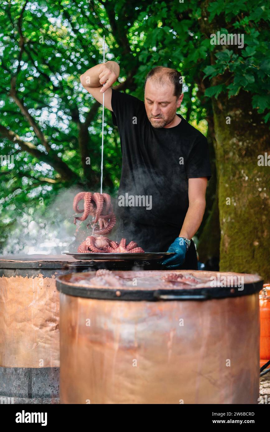 A serious chef expertly handles a large octopus with a hook, lifting it ...