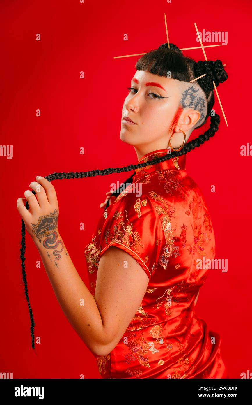 Woman in traditional red cheongsam dress holding her braid against a ...