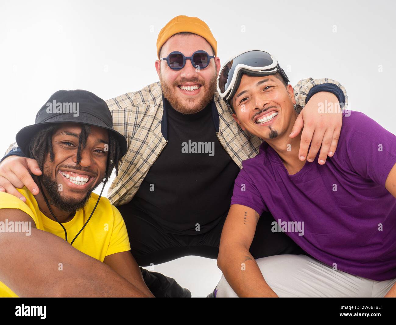 Three cheerful men wearing casual and stylish attire smile and embrace ...