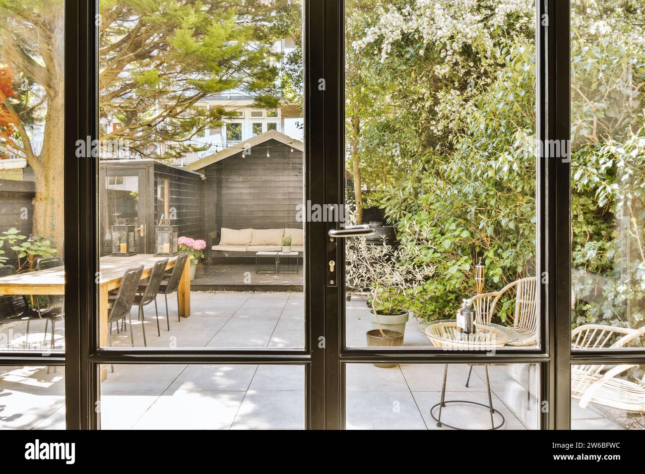 Backyard with wooden shed and furniture surrounded with lush trees and ...