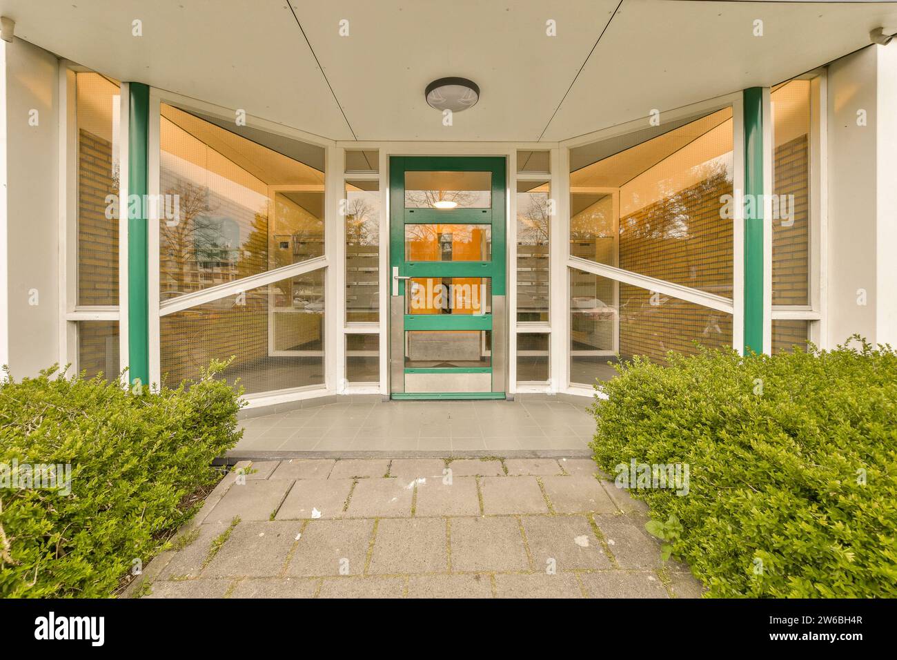 Plants and bushes growing at entrance of modern office building with ...
