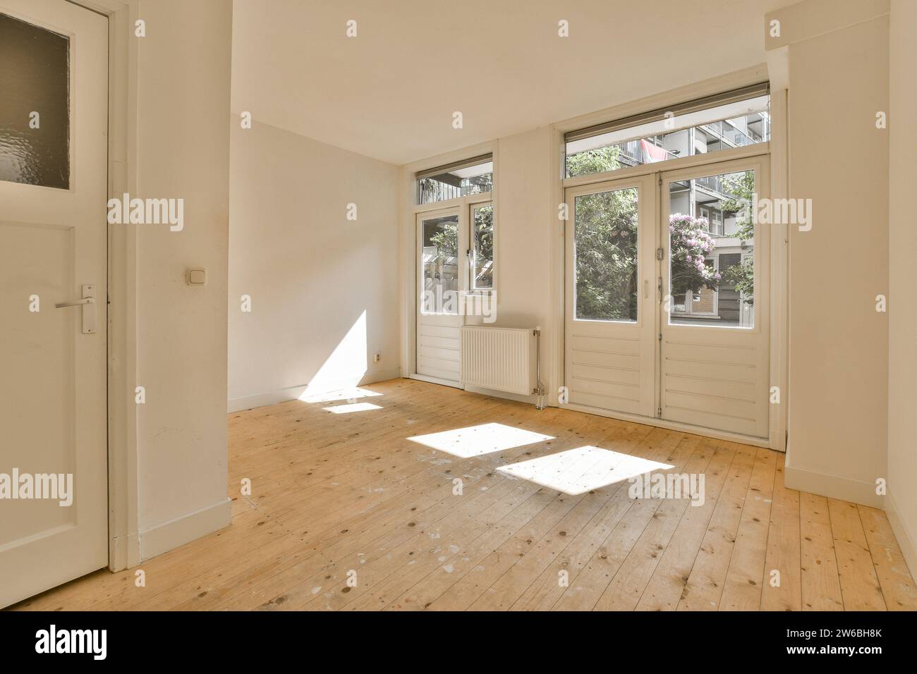 Sunlight falling through window on stained hardwood floor in empty ...