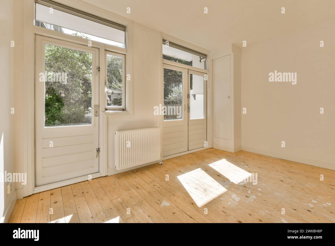 Sunlight falling through doors on stained floor in empty unfinished ...