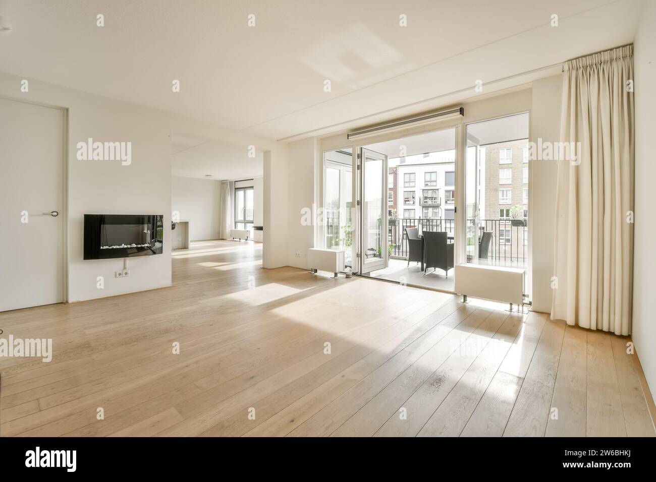 A spacious, well-lit modern living room featuring hardwood floors, open ...