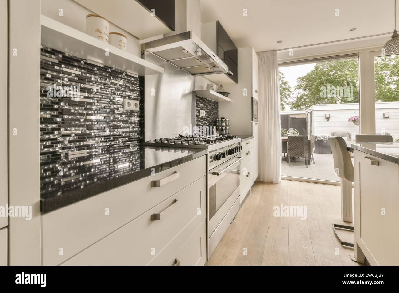 Clean counter with stove burners below range hood by large window in ...