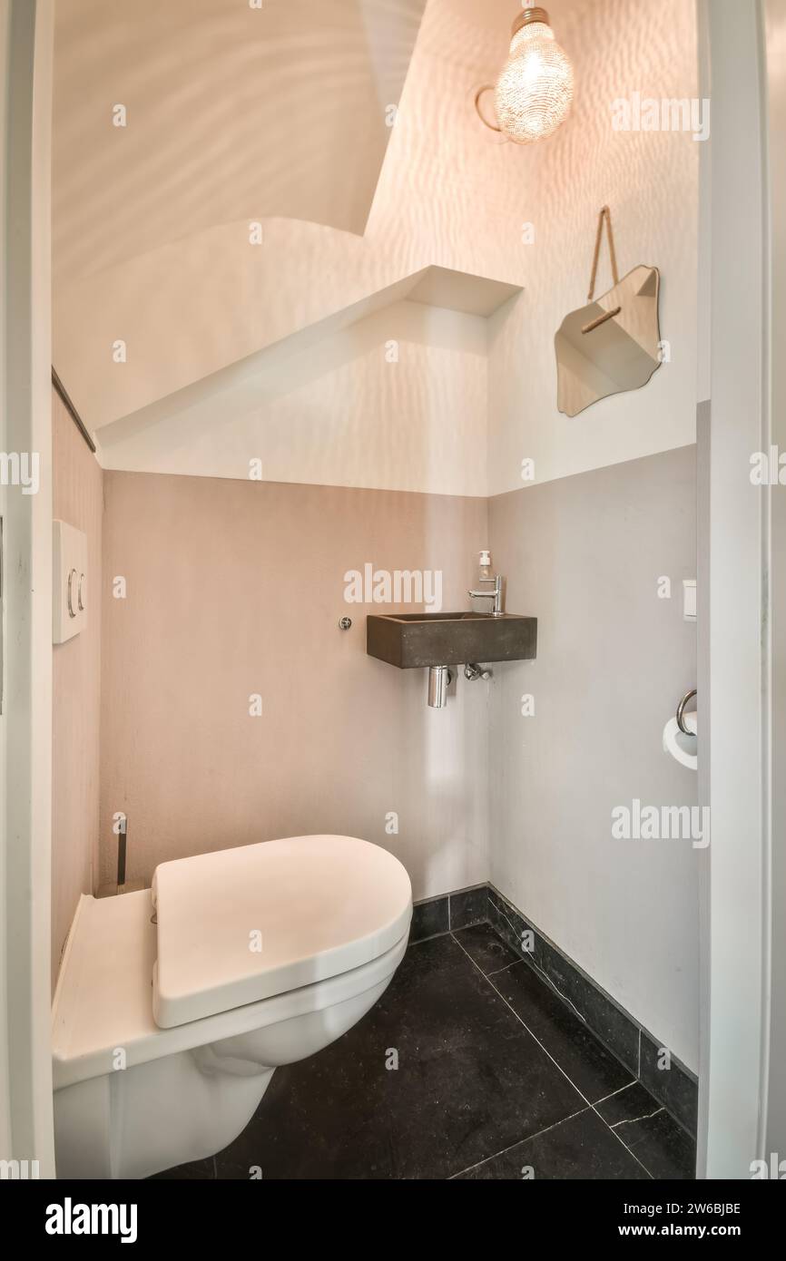 Interior of illuminated light bulb hanging over toilet bowl with sink ...
