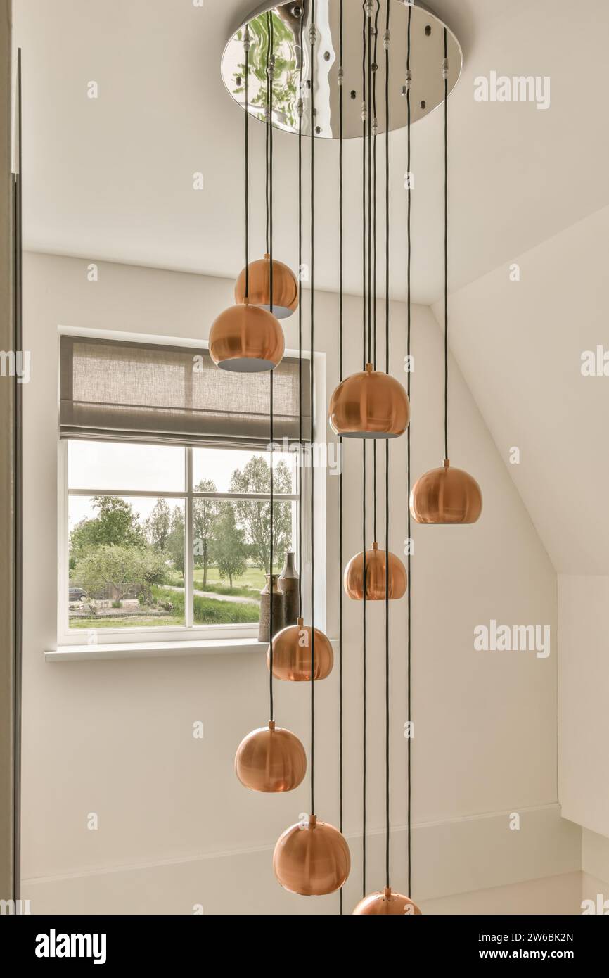 Contemporary pendant light hanging from white ceiling near window with ...