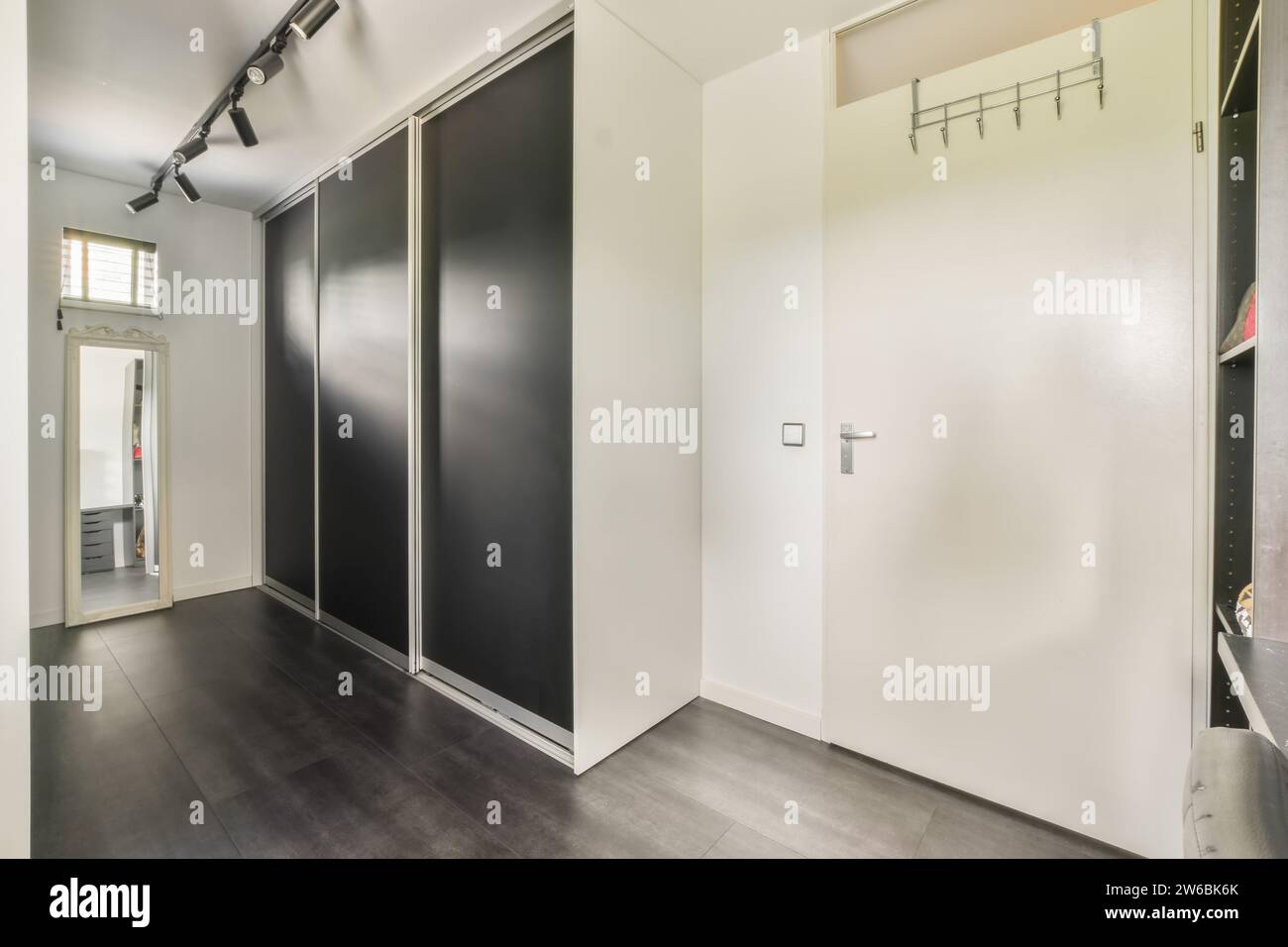 Contemporary hallway boasting a large sliding wardrobe with black doors ...