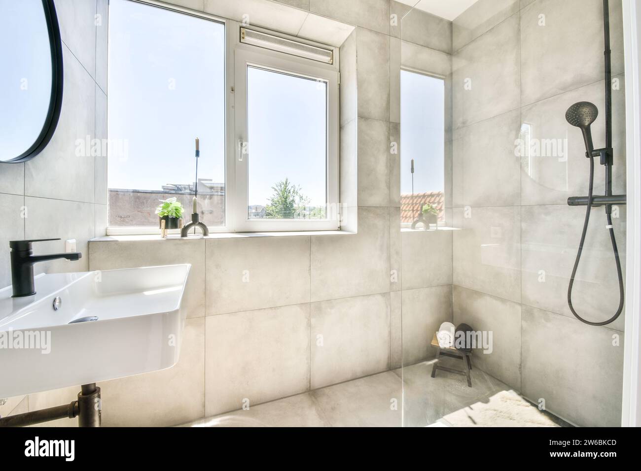 Shower booth with glass wall with ceramic sink by decor on window sill ...