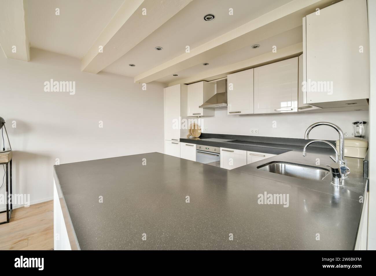 A contemporary kitchen space featuring sleek white cabinetry, a dark ...