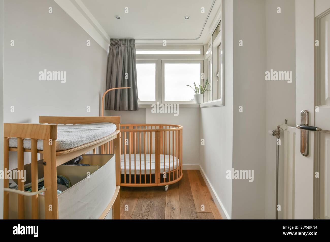 Wooden empty baby cot in cozy bedroom of luxurious apartment with white ...