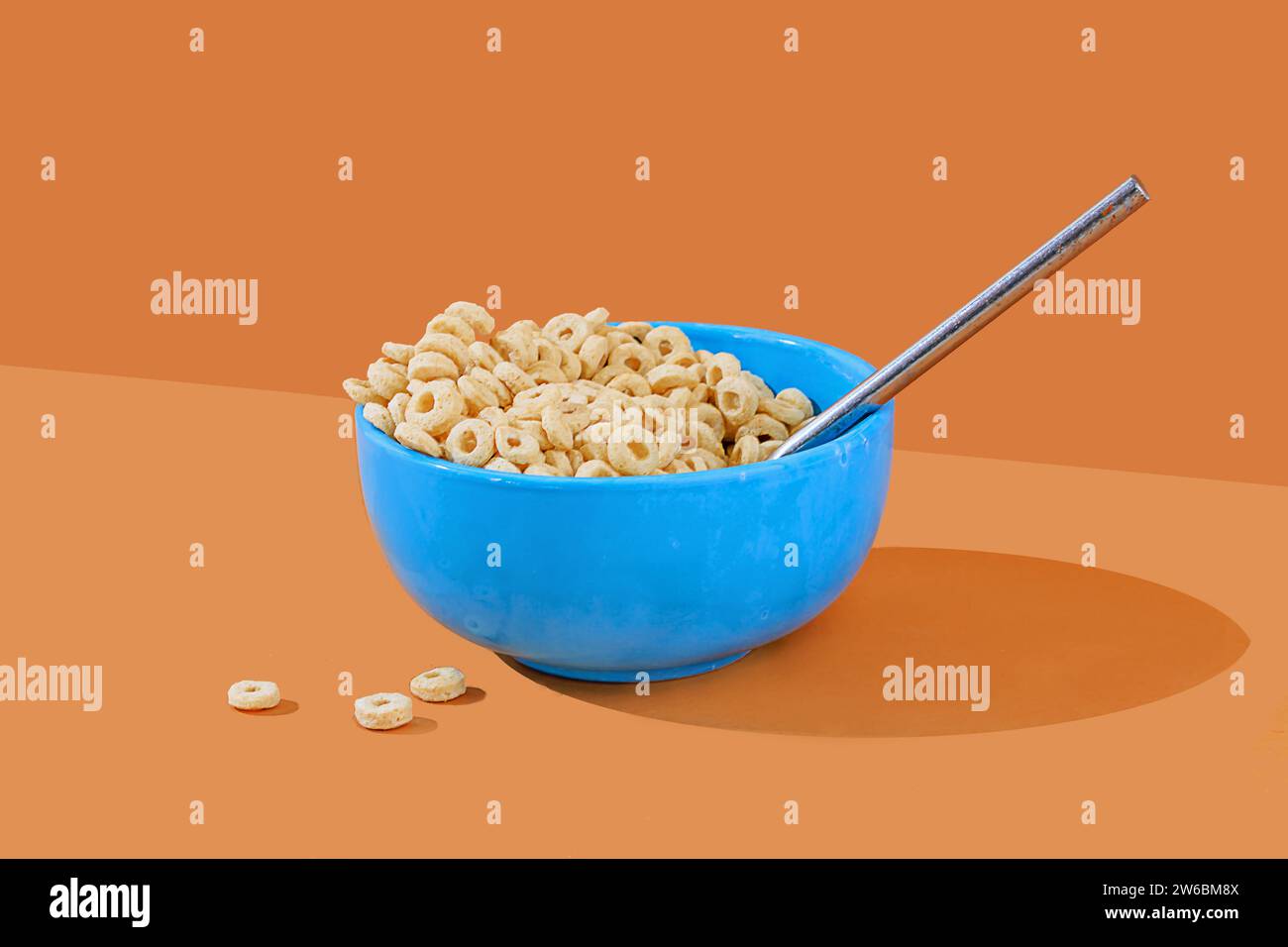 A blue bowl filled with loop-shaped cereal and milk, accompanied by a ...