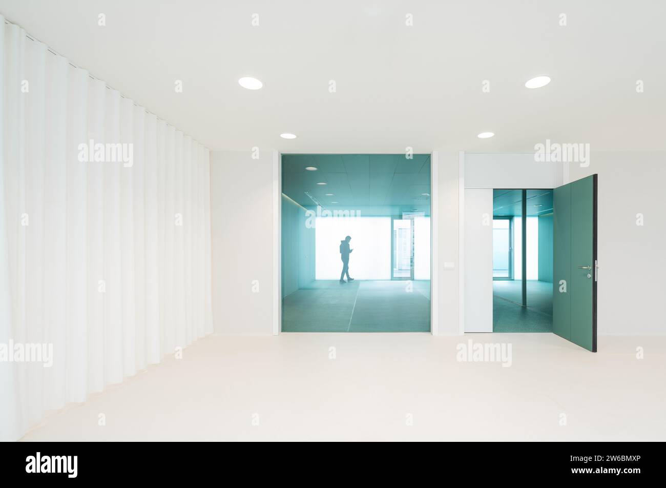 Side view of anonymous Man seen through glass wall in empty white room ...
