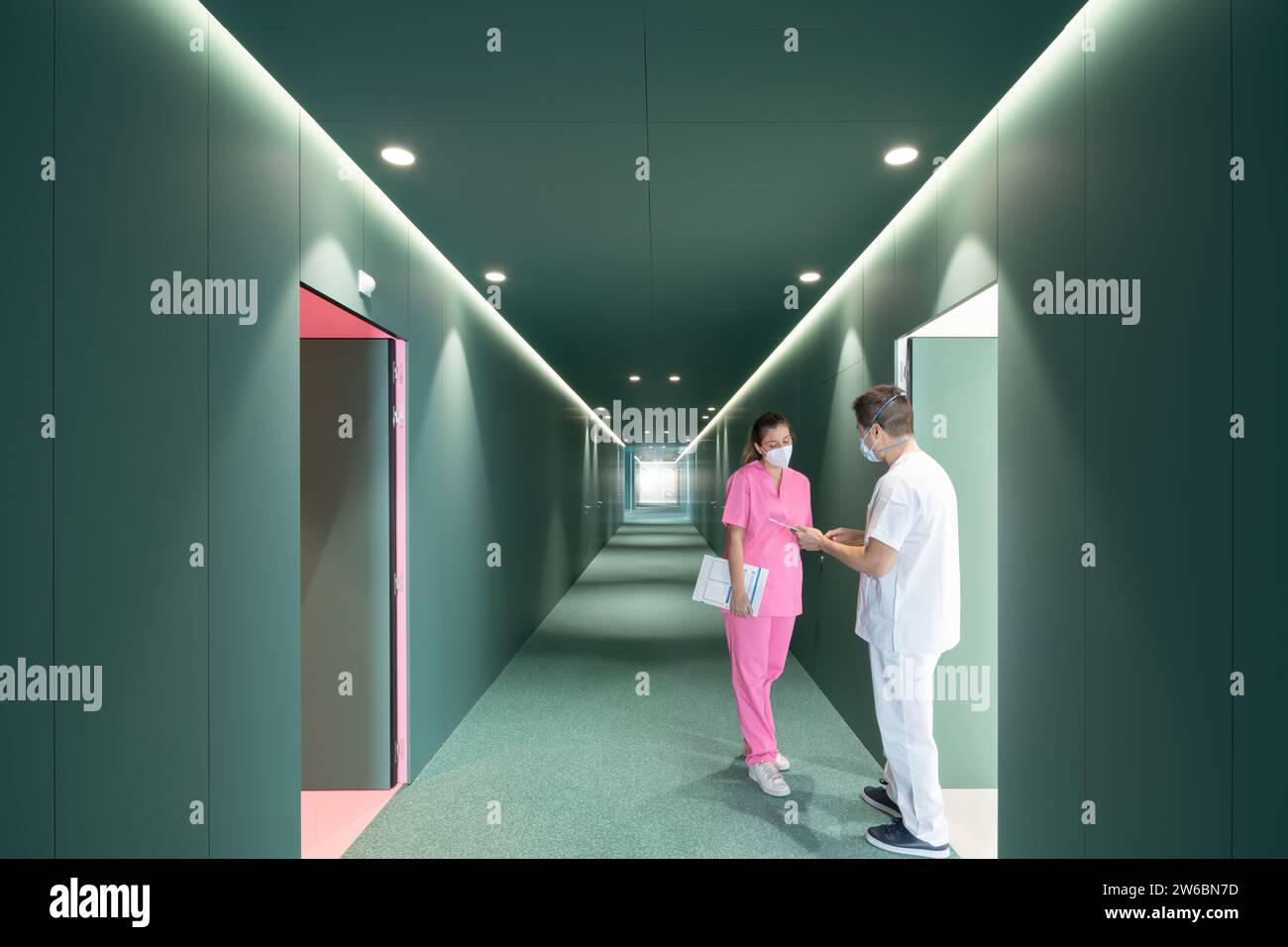 Female nurse in pink uniform and mask and male surgeon discussing over ...